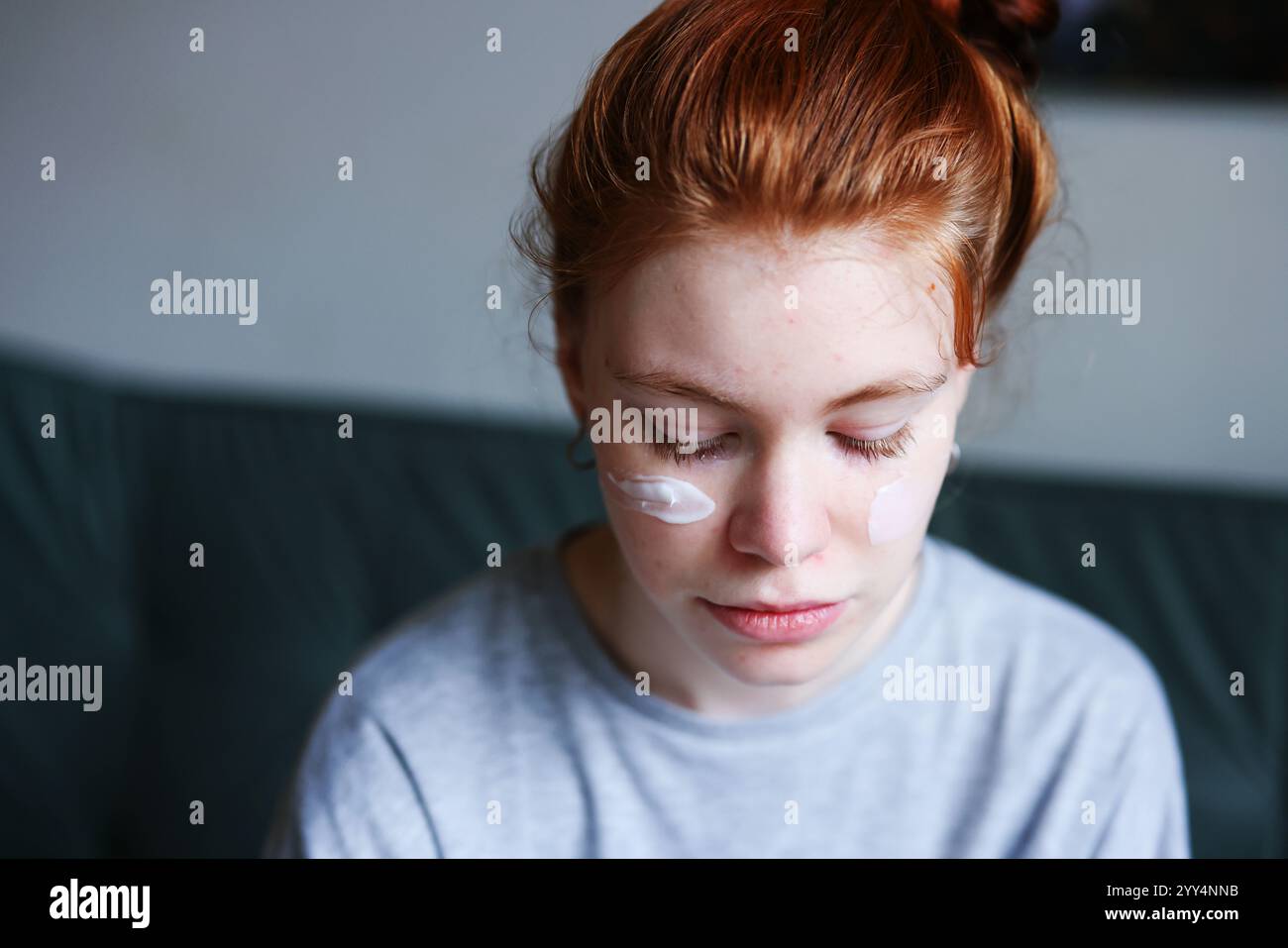 Girl caring of her beautiful skin on the face. Applying moisturizer on ...
