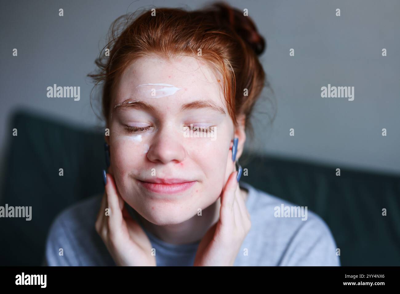 Girl caring of her beautiful skin on the face. Applying moisturizer on ...