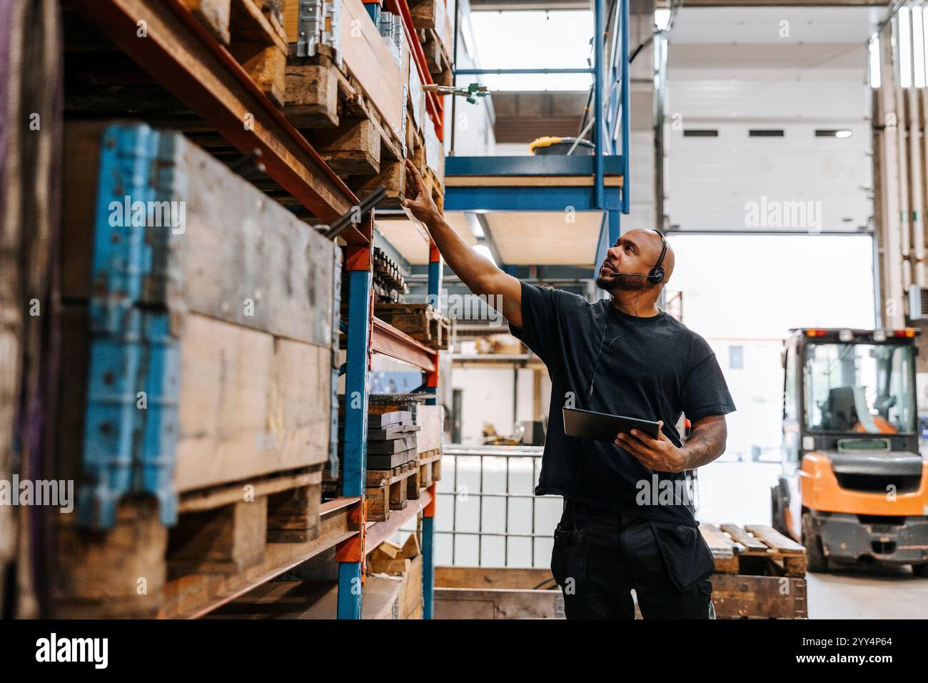 Front view of male worker wearing headset while taking inventory in ...