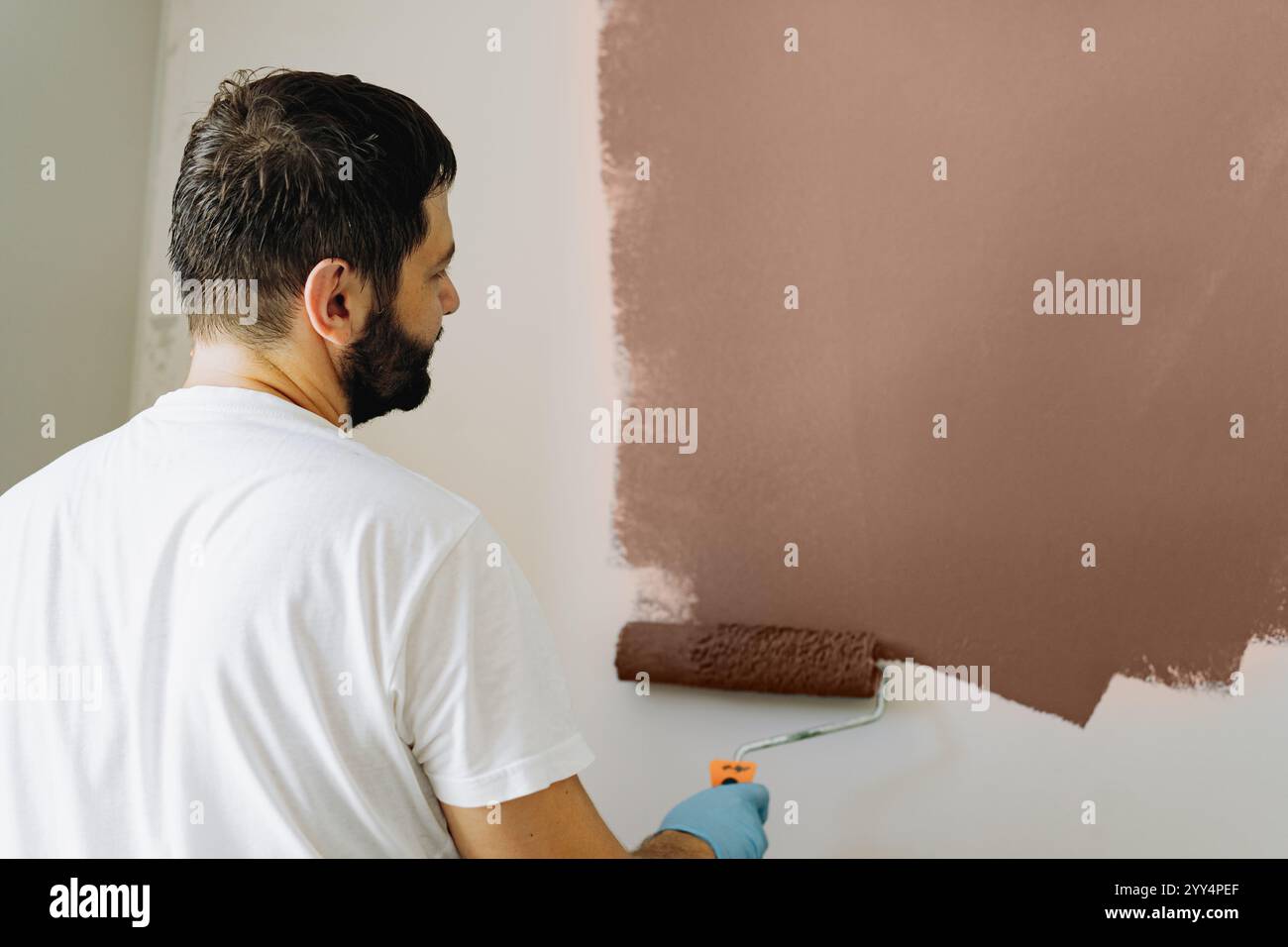 man painting wall pantone 2025 mocha mousse colour. home renovation ...