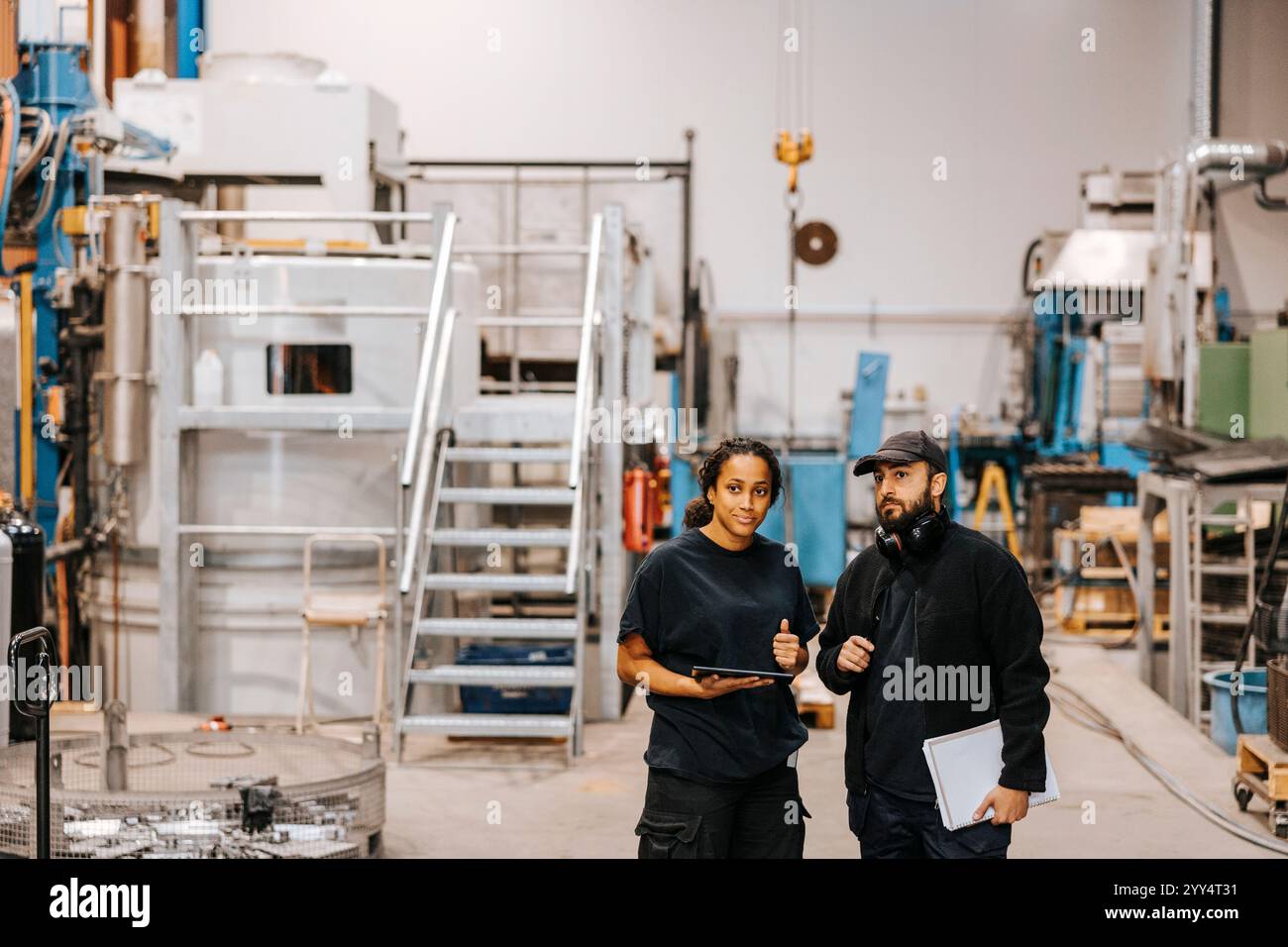 Male worker discussing strategy with female coworker in manufacturing ...