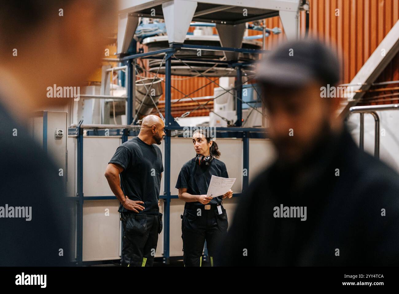 Mature man with arms akimbo standing next to female colleague while ...