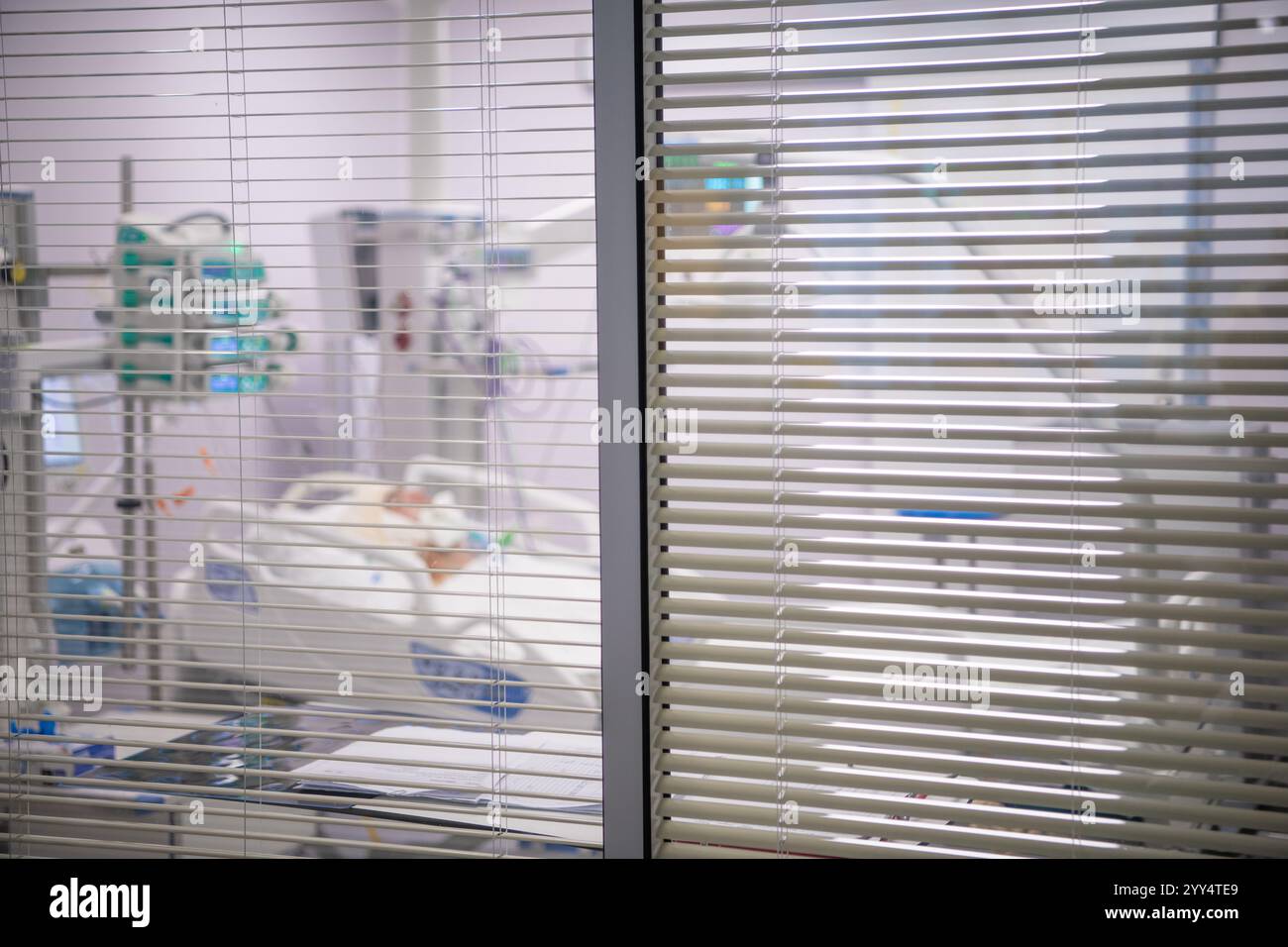 Look trough window sunblind to blurred patient in bed and medical ...