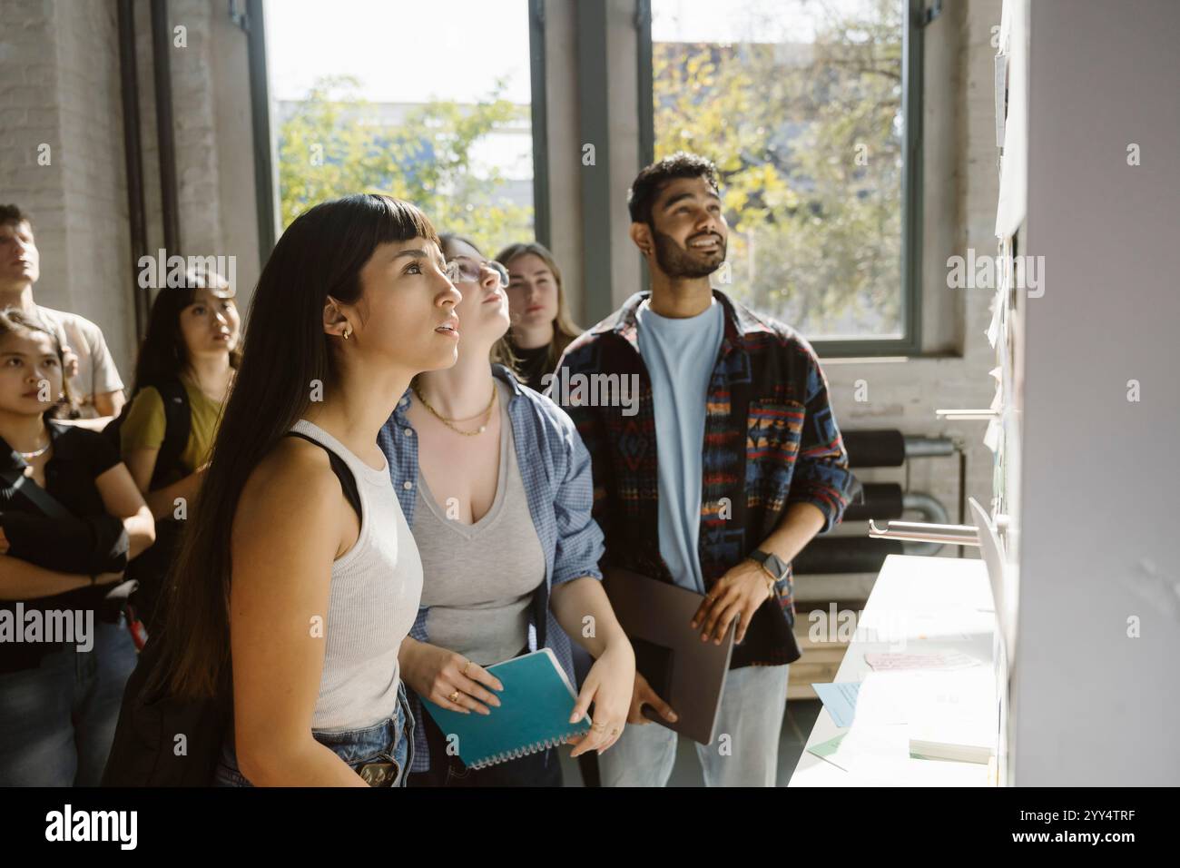 Group of multiracial university students reading bulletin board in ...