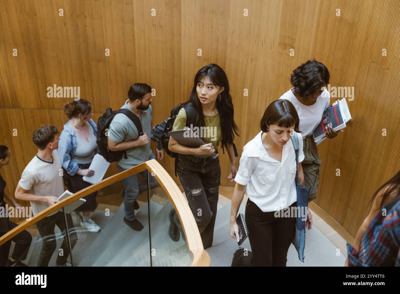 High angle view of multiracial college students moving up stairs in ...