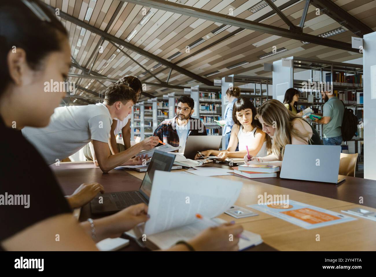 Multiracial male and female university students doing assignment in ...