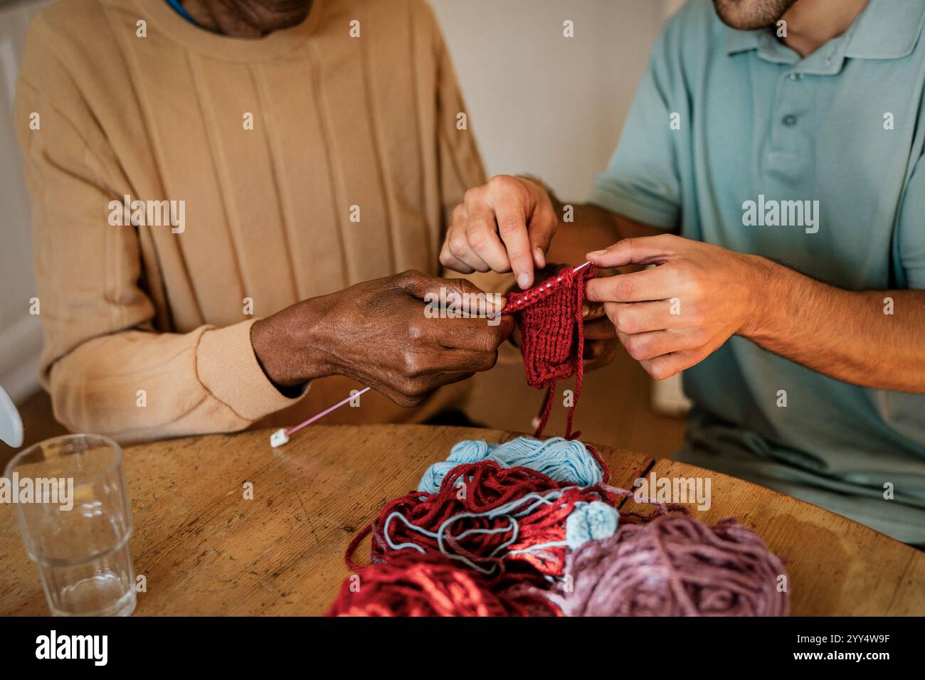 Midsection of male nurse doing knitting with elderly male at home Stock ...