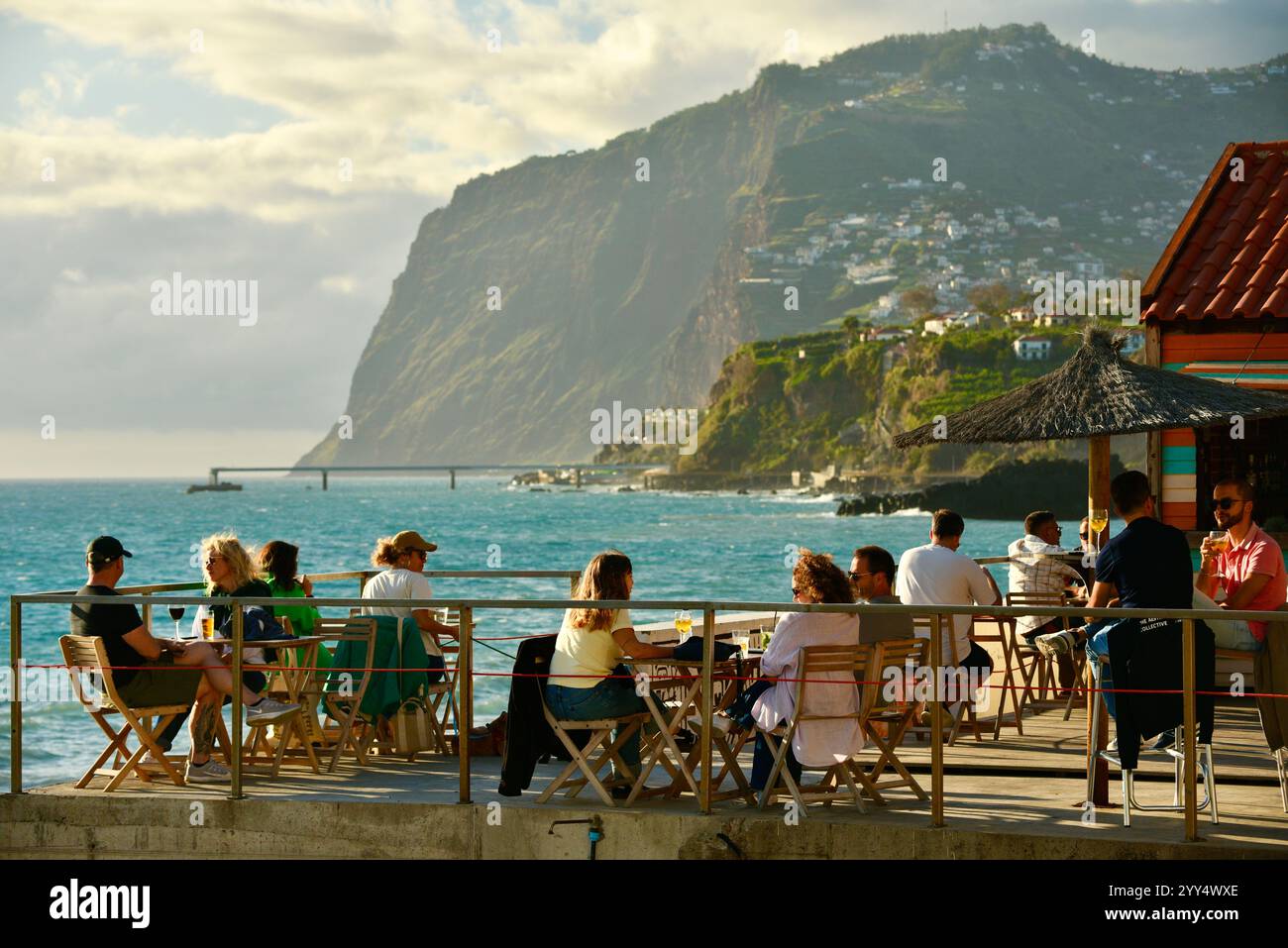 Man and women enjoying cocktails, beer, wine and meals in an oceanside ...