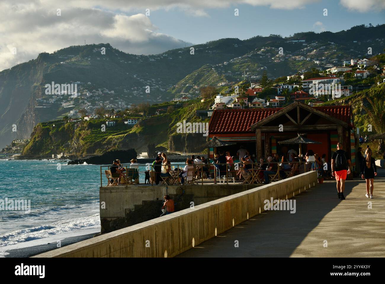Man and women enjoying cocktails, beer, wine and meals in an oceanside ...