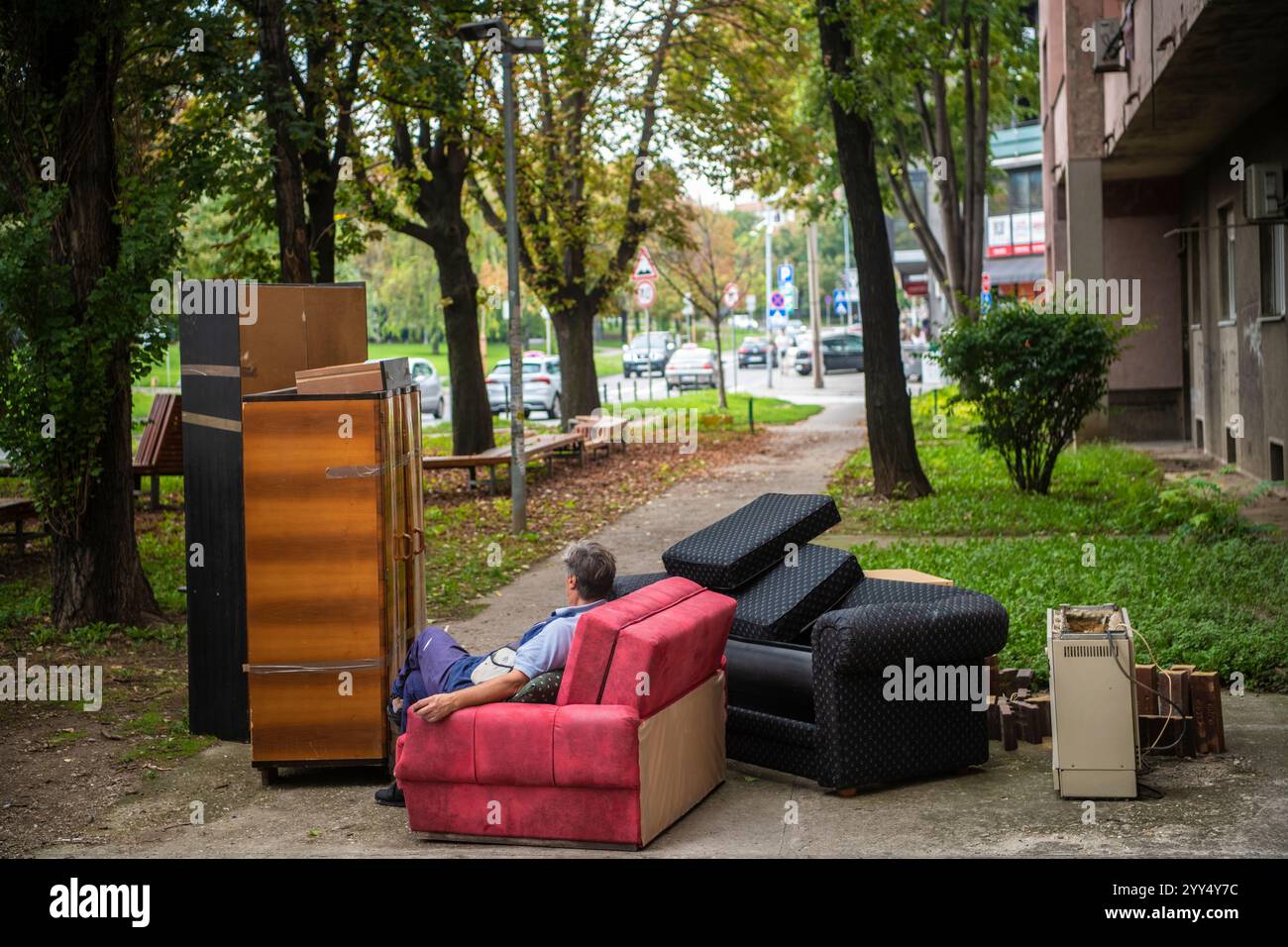 Moving day. Man sitting on Old furniture, packed boxes and household ...