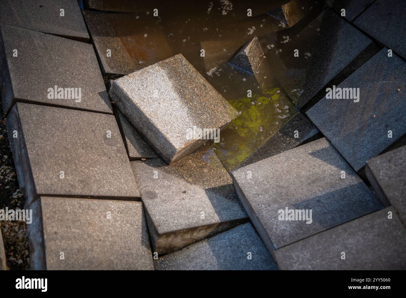 Broken pavement without some stones, filled with mud and water ...