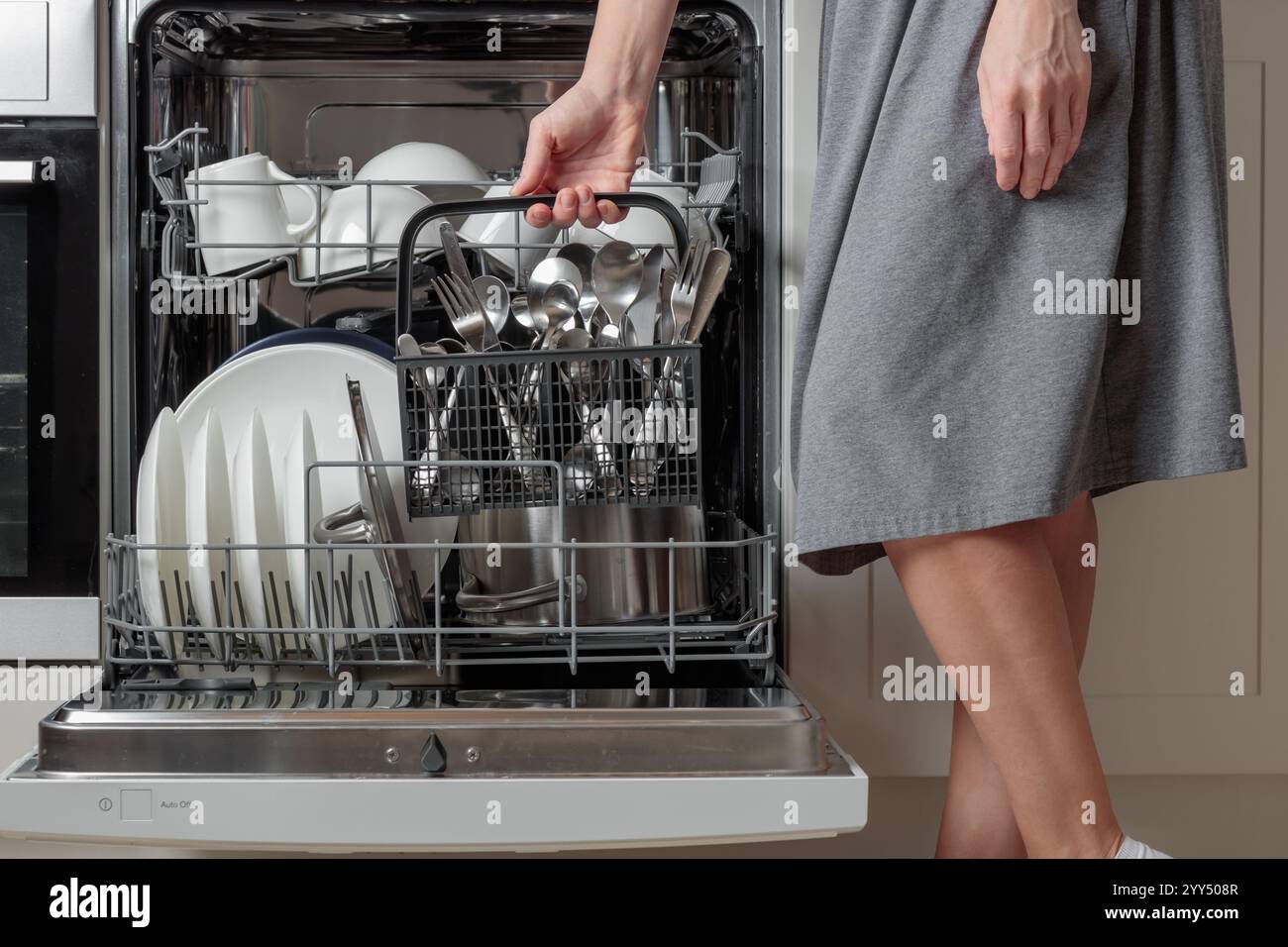 Woman's hands emptying, unloading a dishwasher, taking out a cutlery ...