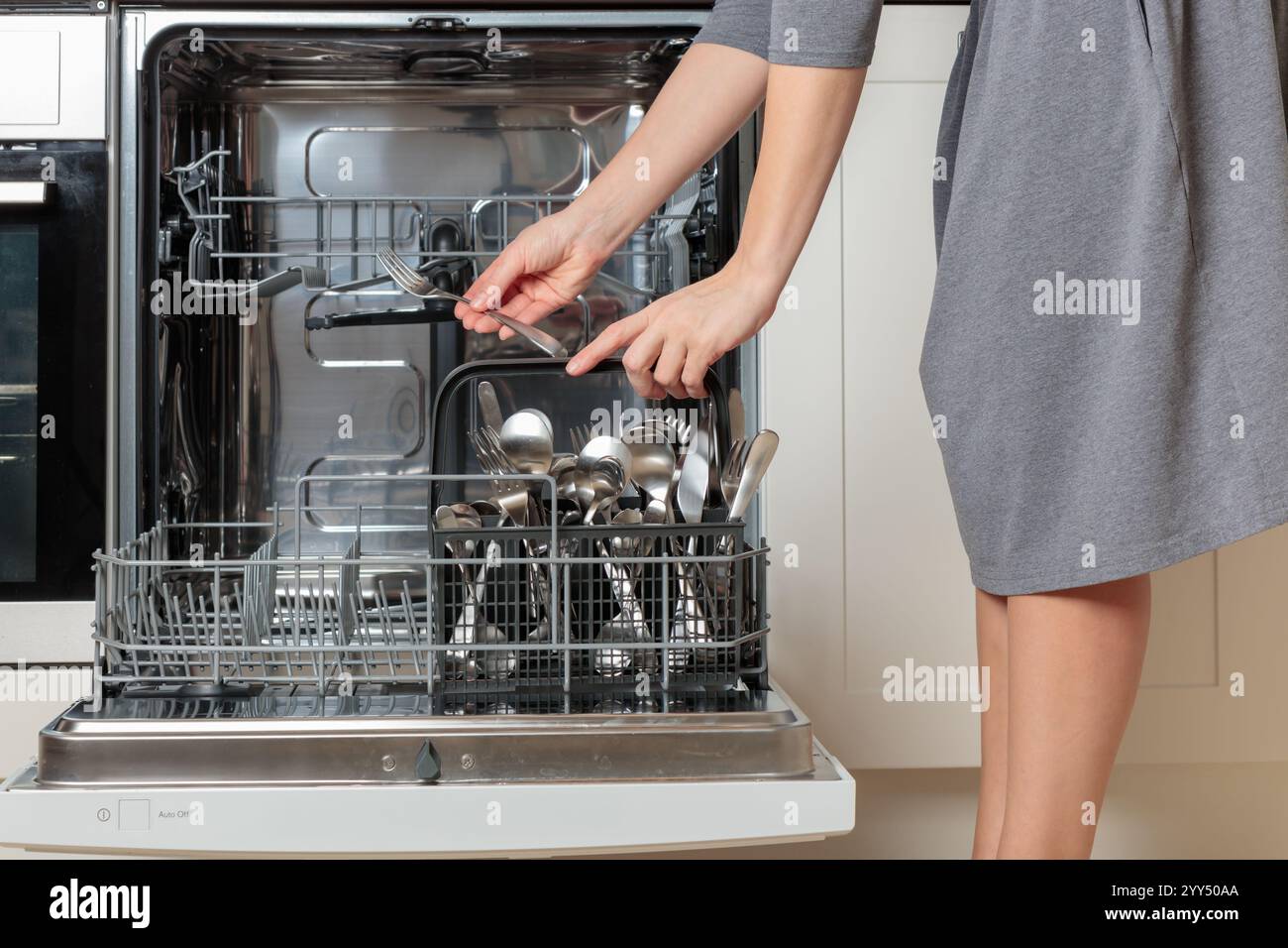 Woman's hands emptying, unloading a dishwasher, taking out a clean fork ...