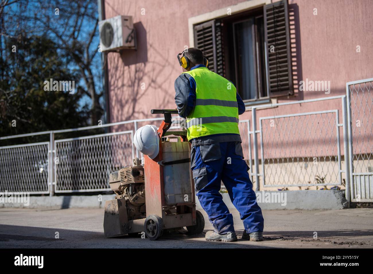 Construction worker cutting asphalt. Worker using diamond saw blade ...