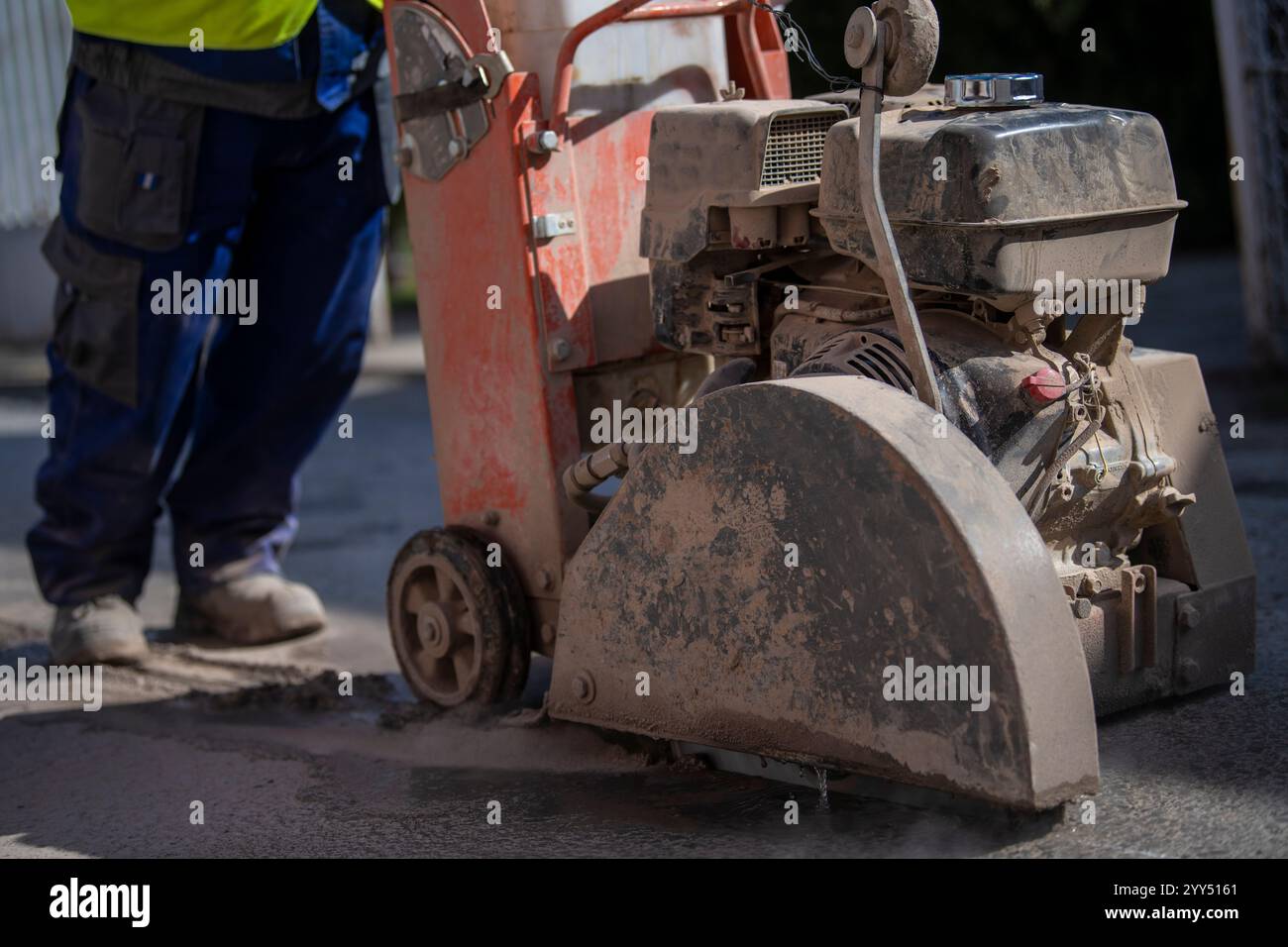 Construction worker cutting asphalt. Worker using diamond saw blade ...