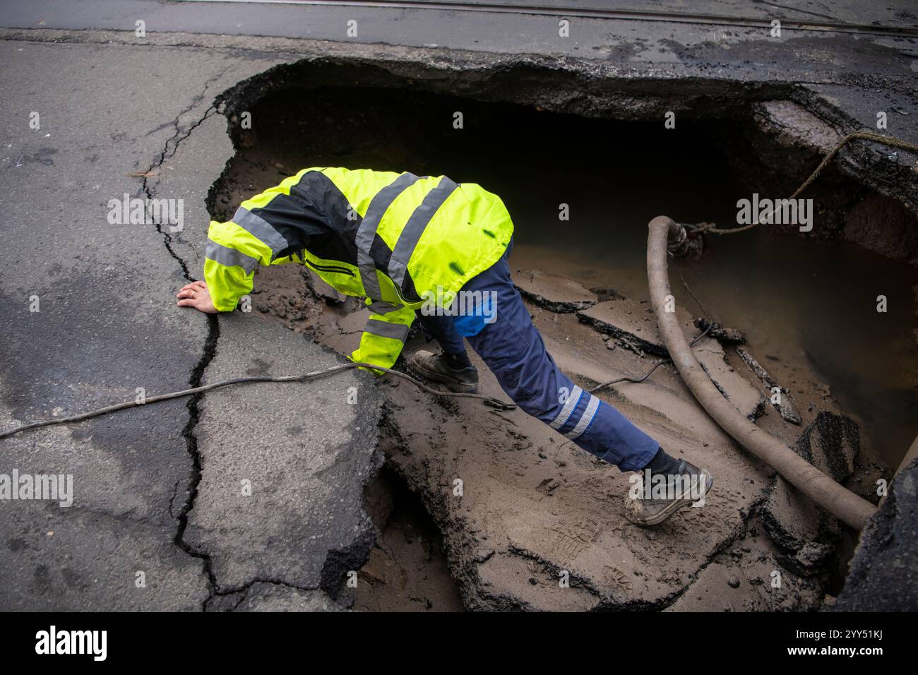 Road construction worker with machines repair Huge sinkhole on busy ...