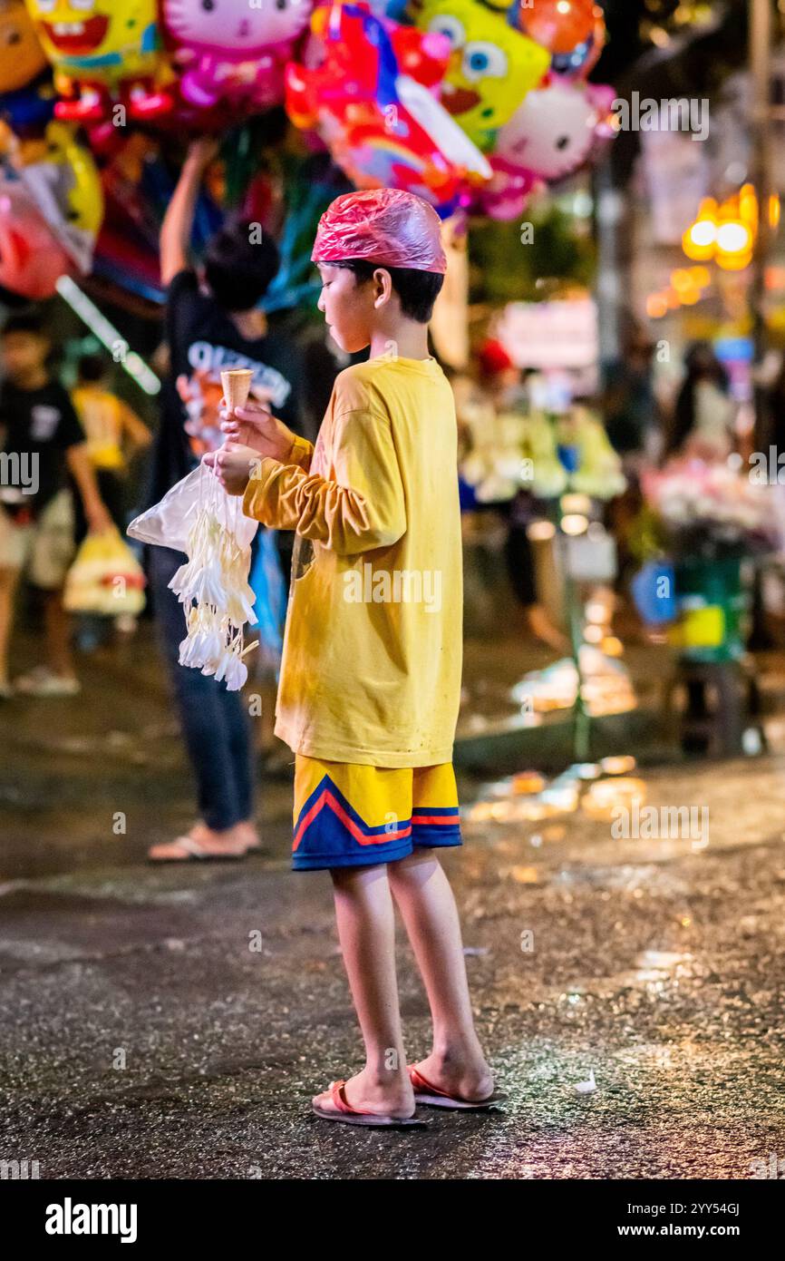 Young filipino boys sell flower garlands to worshippers outside the ...