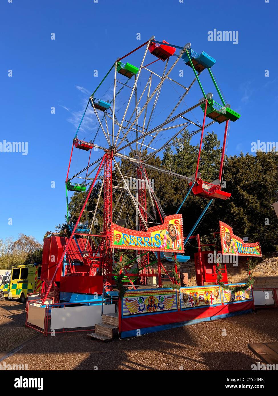 Fun fair big wheel Ferris wheel ride in the sun with blue sky behind ...