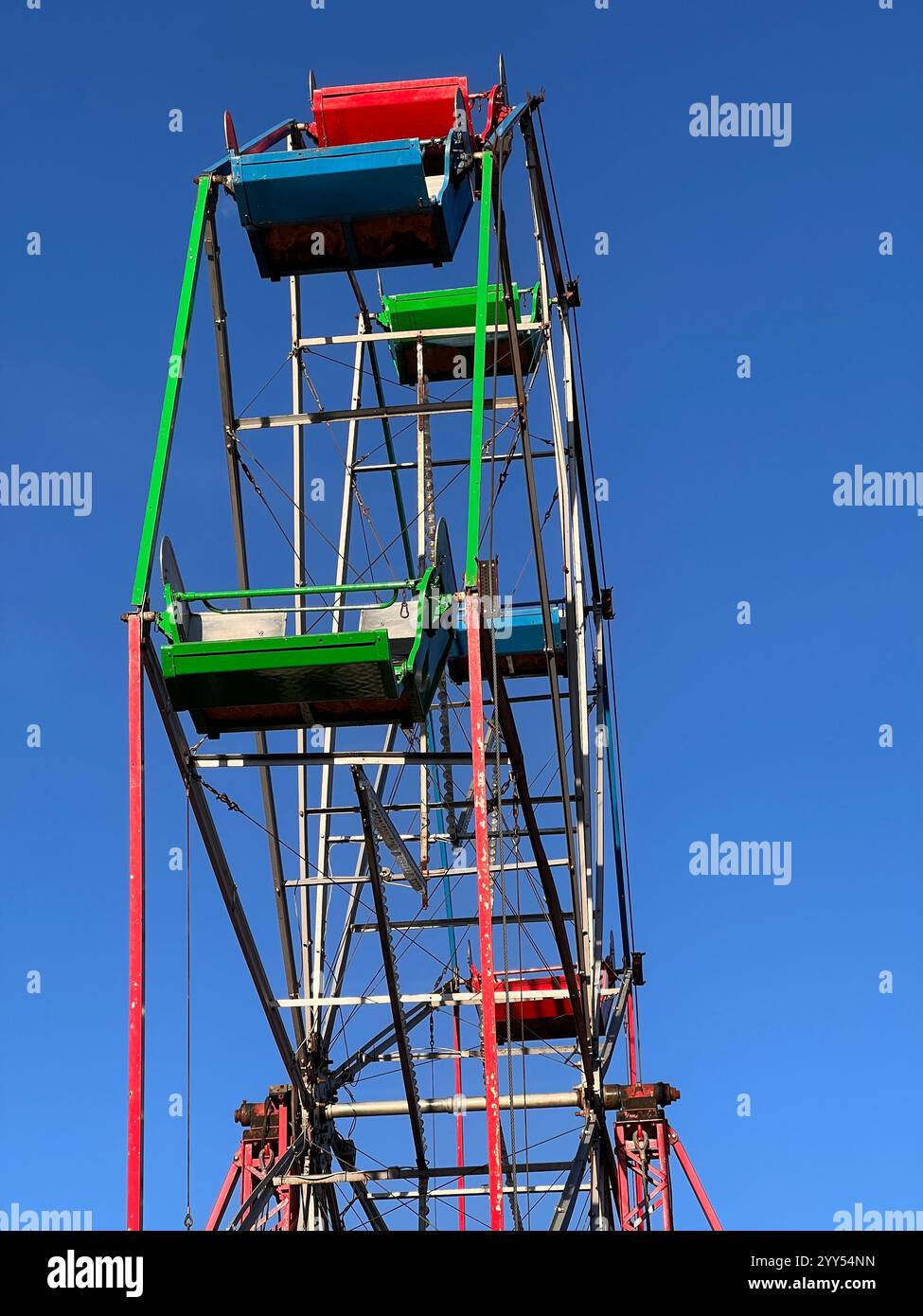 Fun fair big wheel Ferris wheel ride in the sun with blue sky behind ...