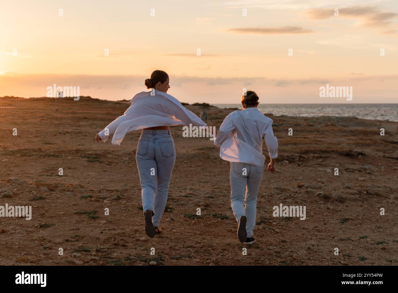 Couple Sunset Beach Run - Two people run towards the ocean during a ...