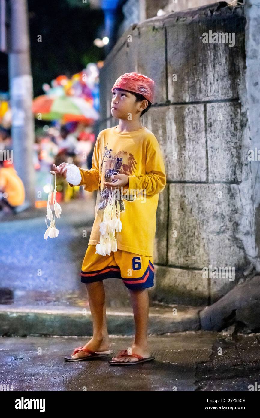 Young filipino boys sell flower garlands to worshippers outside the ...