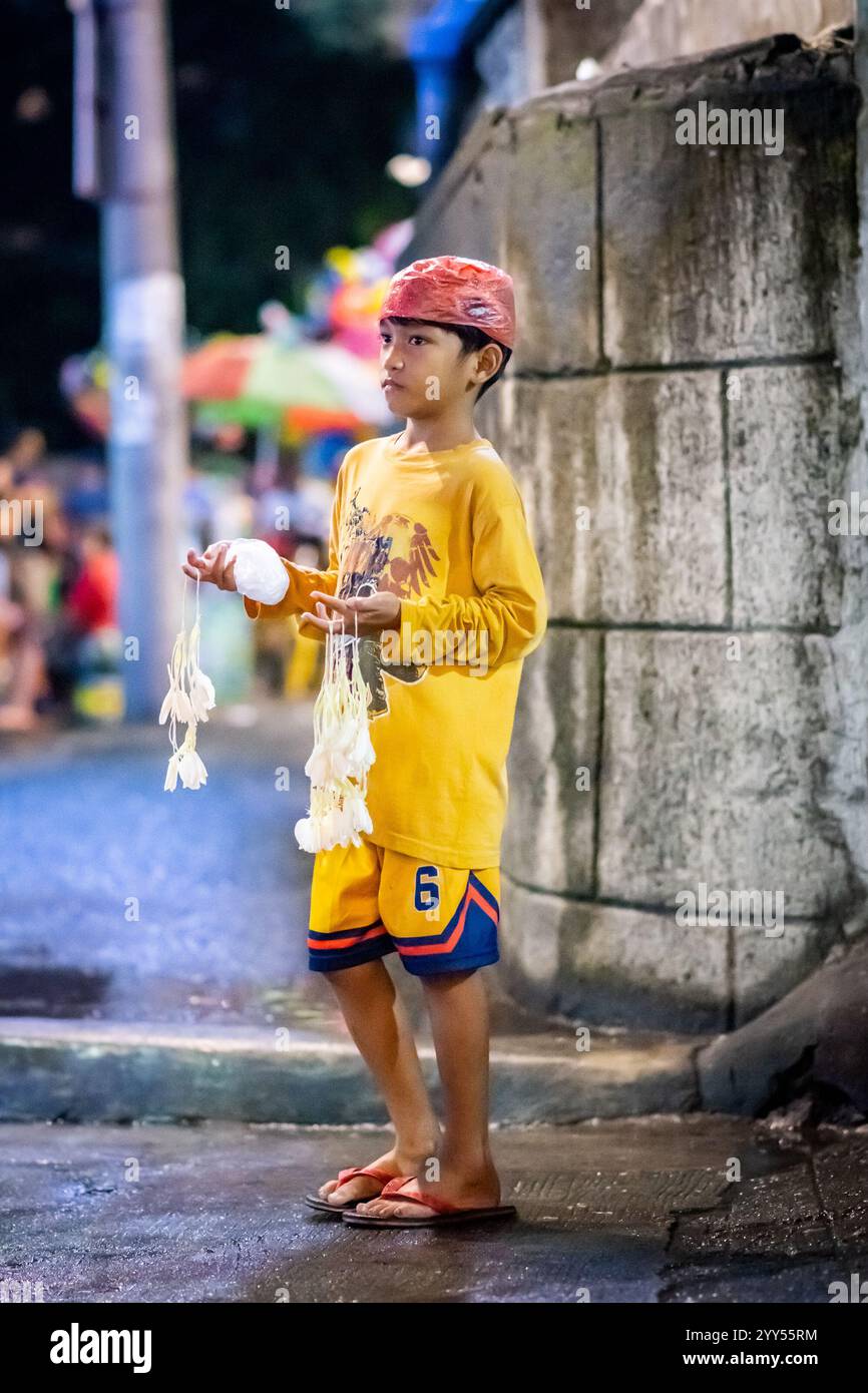 Young filipino boys sell flower garlands to worshippers outside the ...