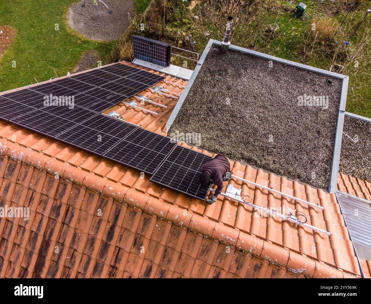 Auf einem Passivhaus aus Holz montiert ein Monteur Solarpanele auf dem Dach. Leutkirch, Baden ...