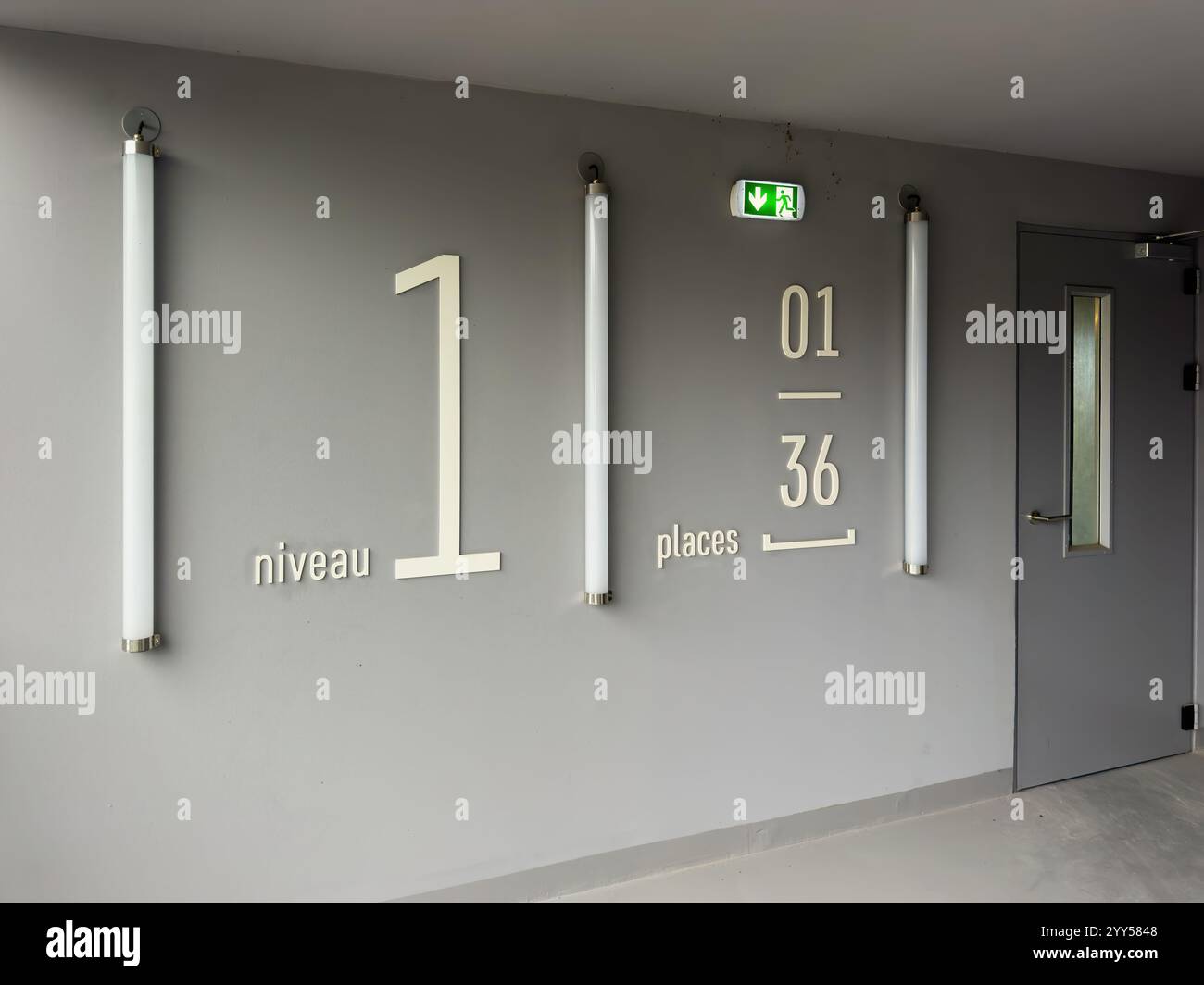 Indoor parking lot signage on a gray wall indicating level one and ...