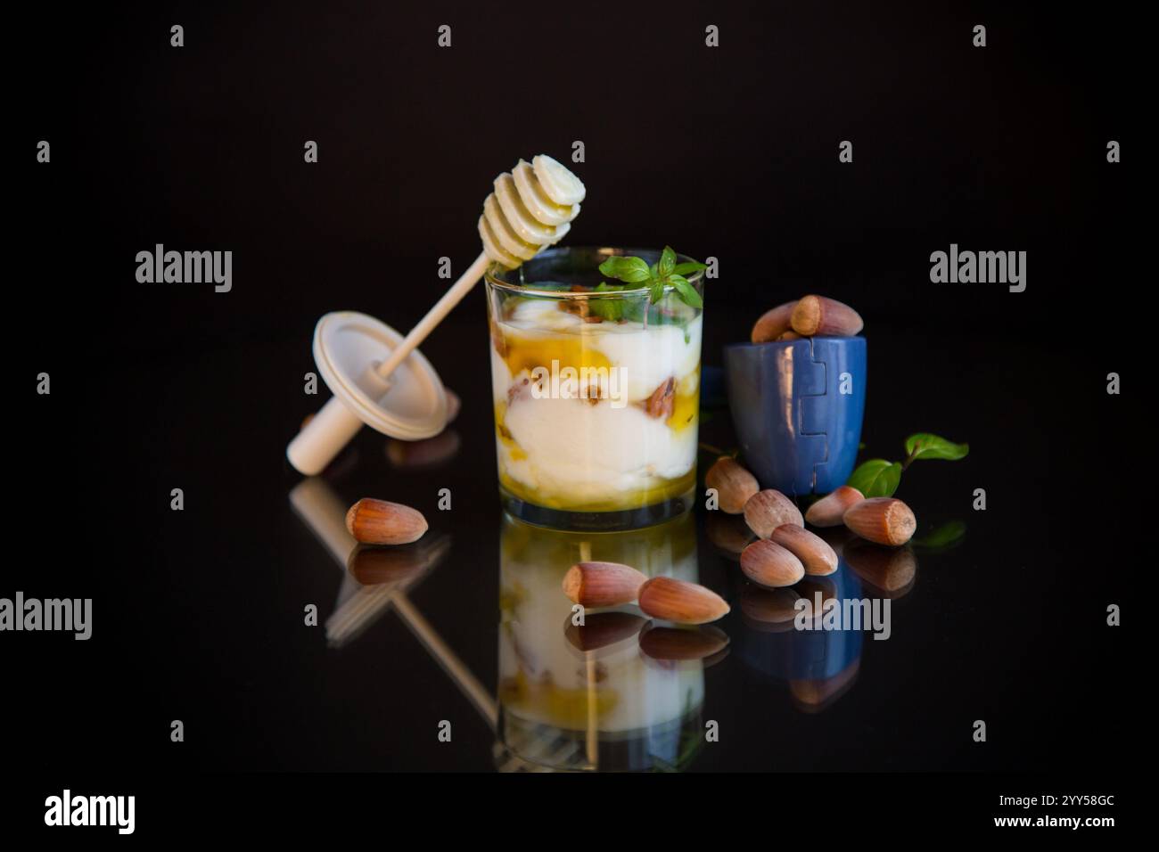 homemade yogurt with kiwi, honey and nuts in a glass, isolated on black ...