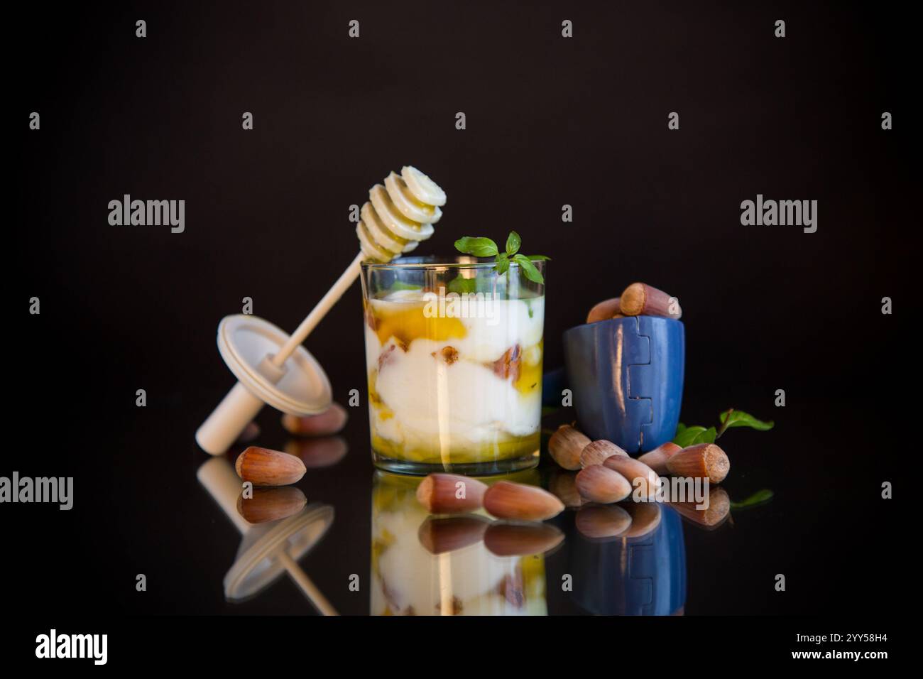 homemade yogurt with kiwi, honey and nuts in a glass, isolated on black ...
