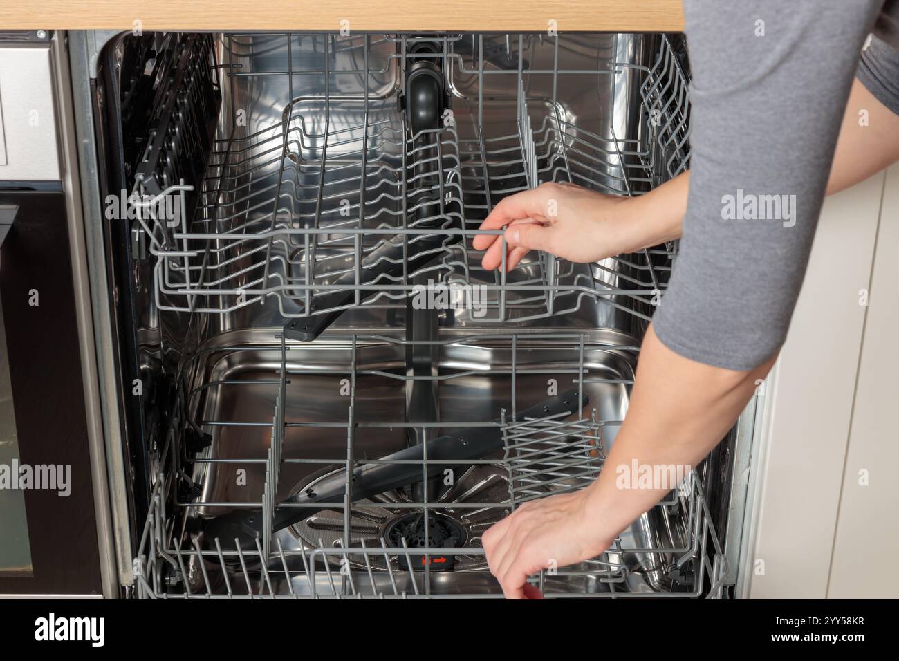 Woman hands opening built-in empty dishwasher with its door open ...
