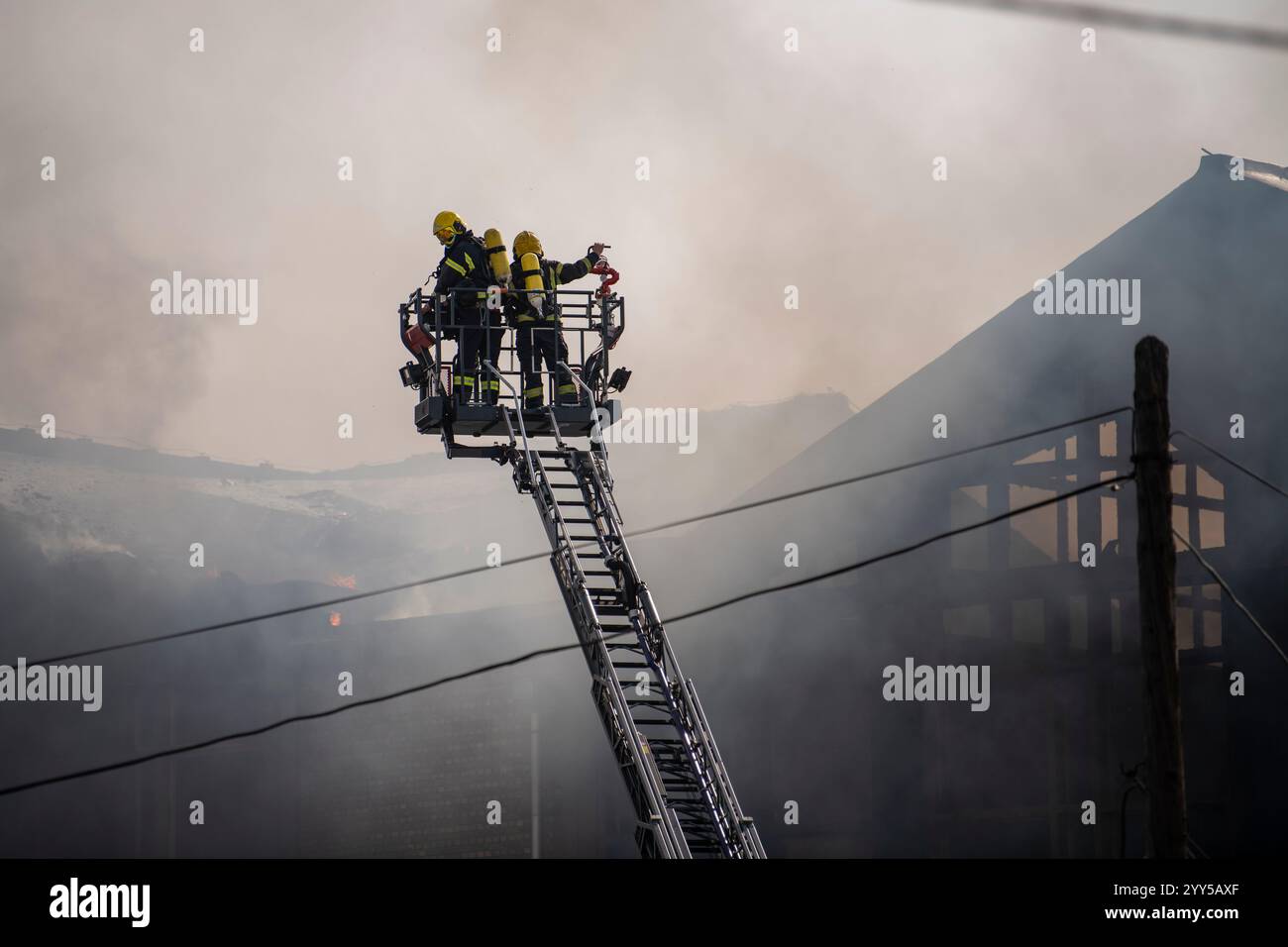 Dramatic scene of Firefighters rising on a mechanical sliding ladder ...