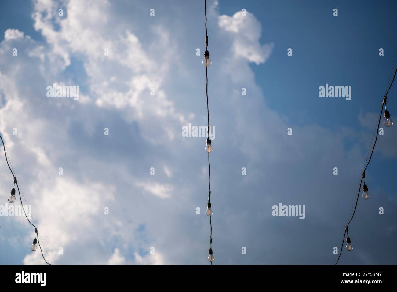 Light bulbs on string wire against beautiful blue cloudy sky background ...