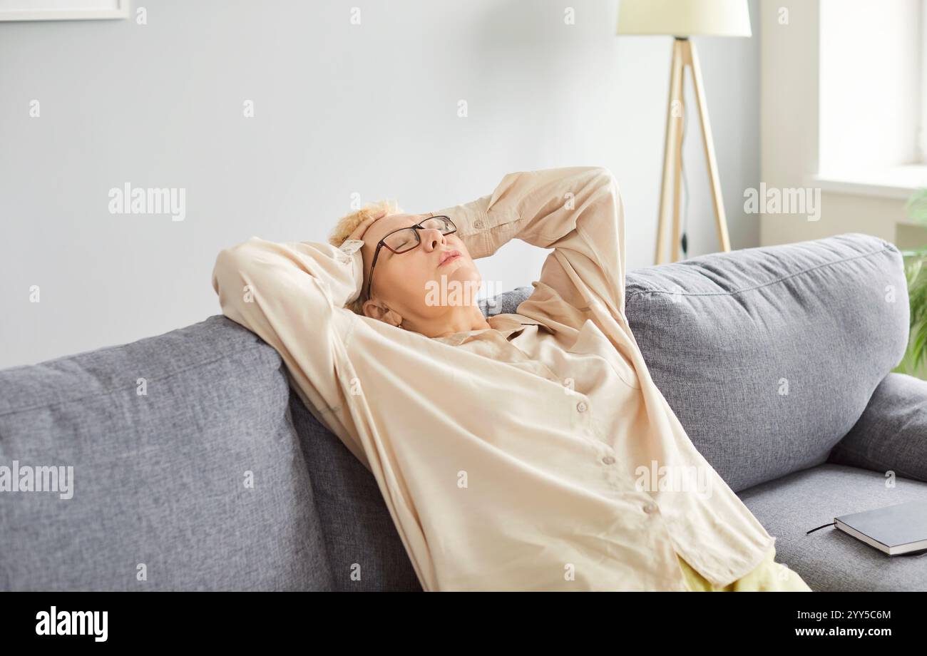 Relaxed woman in beige clothes and glasses taking break, resting on ...