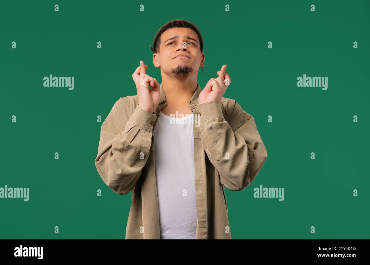 Adult 30s man praying with crossed fingers on green background. Guy ...