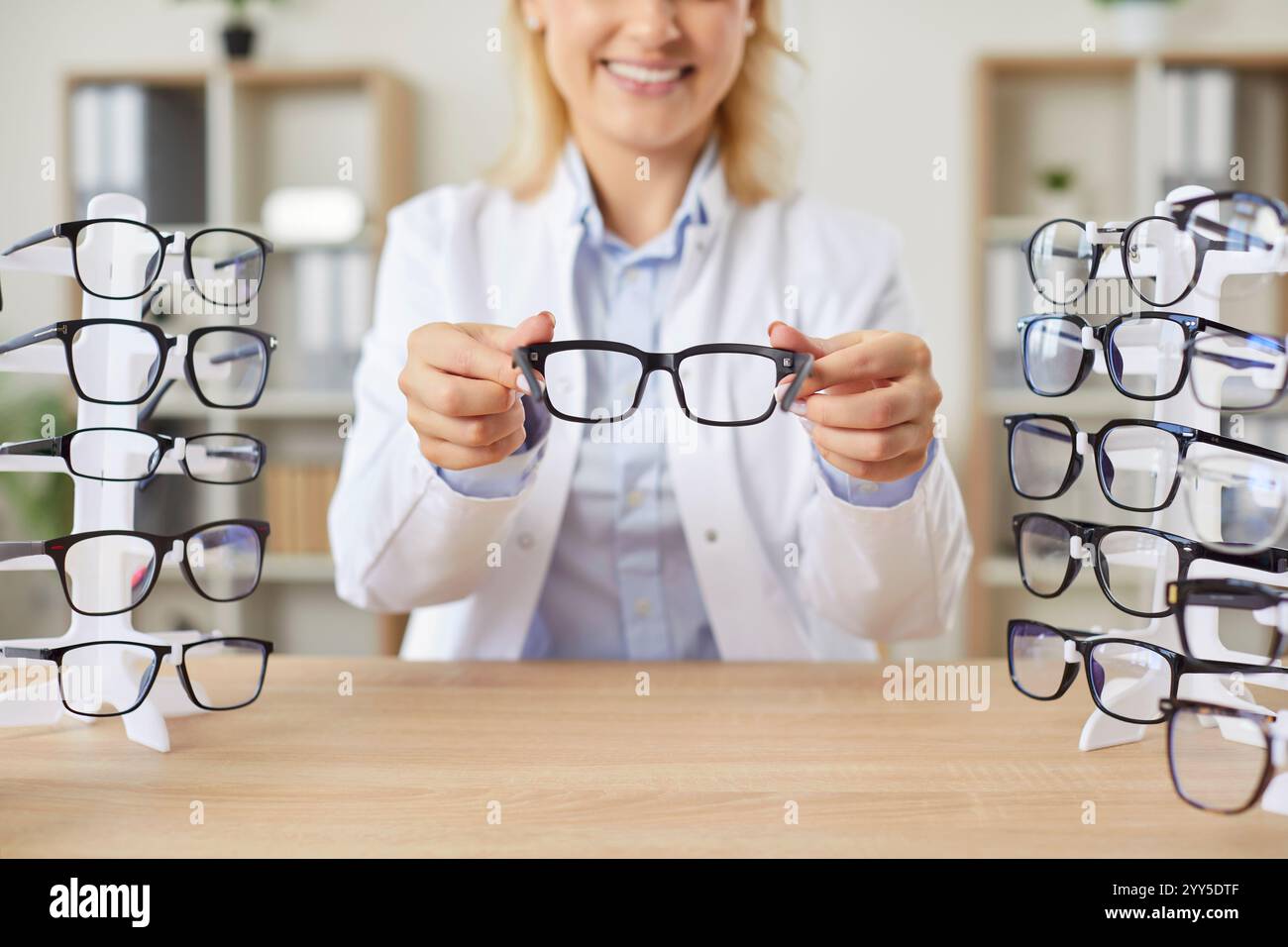 Young happy optician doctor holding eyeglasses in hands working in ...