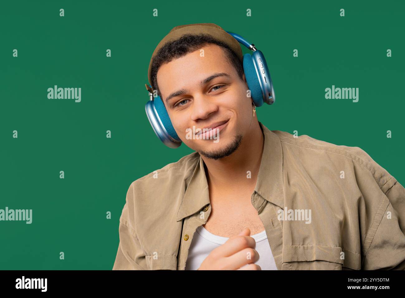 Positive mixed race man listening music, enjoying dance with modern ...