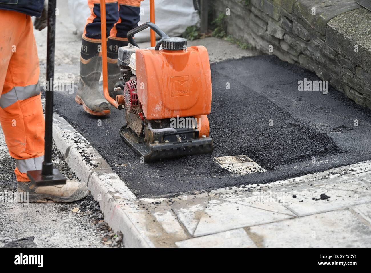 Construction workman hand laying tarmac, using vibrating plate ...