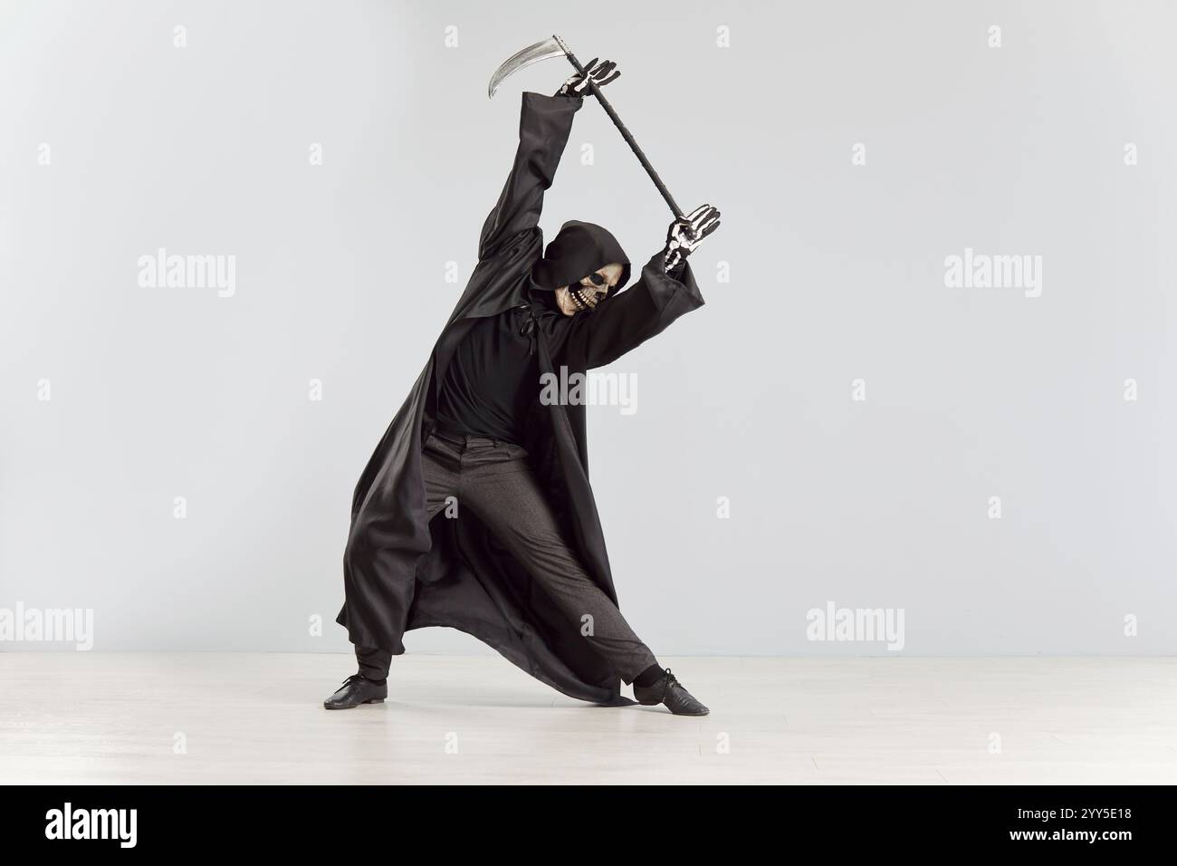 Man in Halloween death costume in black cloak with hood having fun on ...