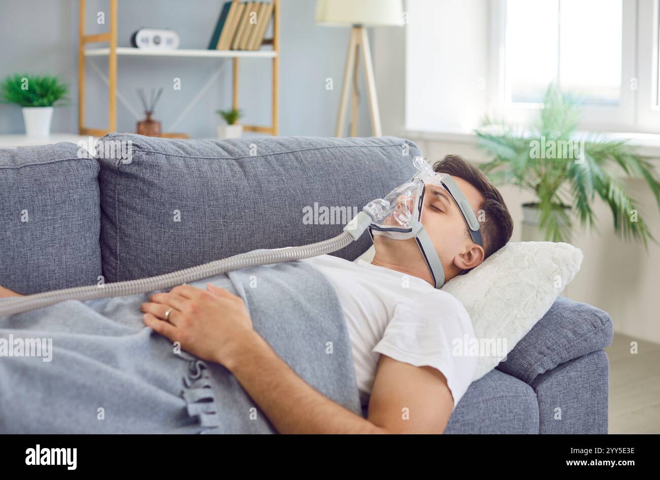 Male patient lying at home sofa wearing medical face oxygen mask ...