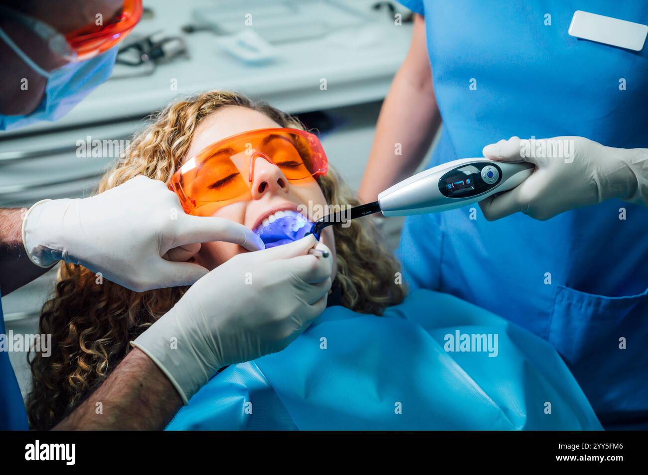 Dentist examining a patient with UV light Stock Photo - Alamy