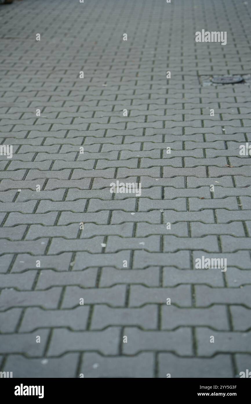 A close-up view of concrete pavement surface, showcasing interlocking pavers arranged in a ...