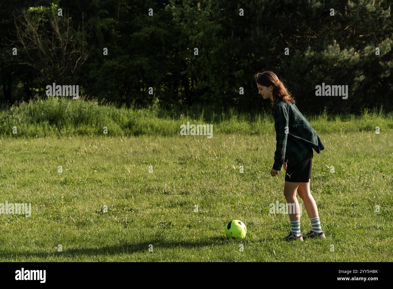 A young girl soccer player playing on the grass field, teenage girl ...