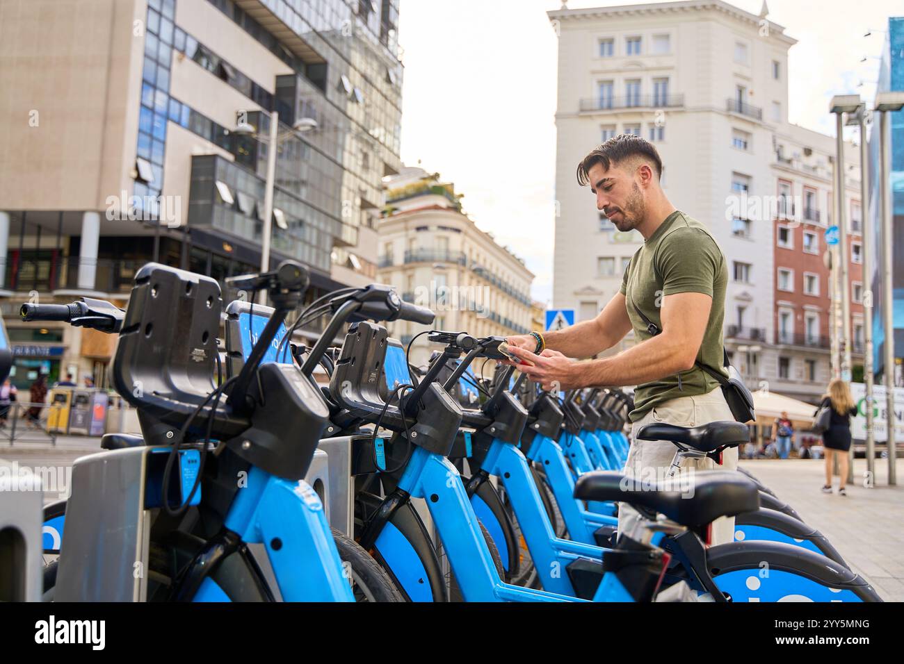 Man using city bike-sharing station in urban environment Stock Photo ...