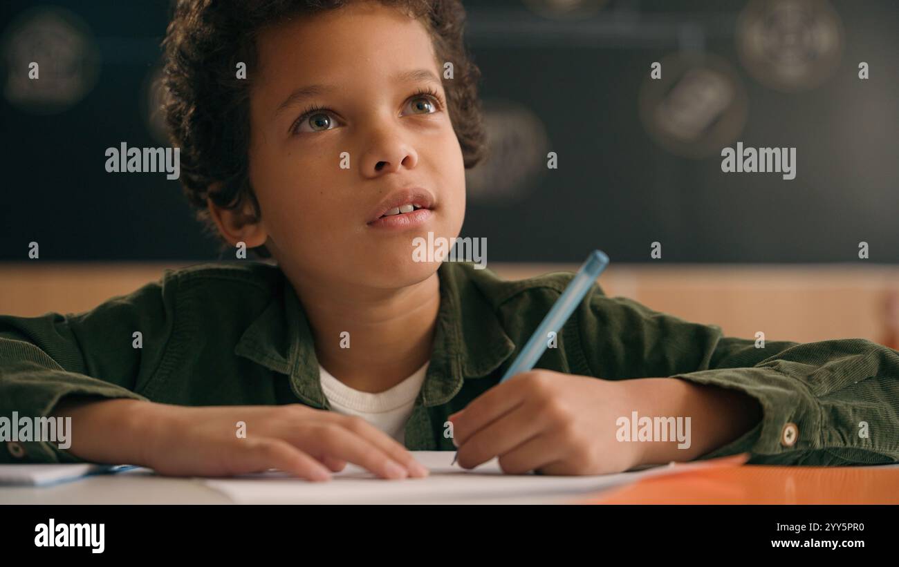 Little African American guy boy writing notes task class lesson primary ...