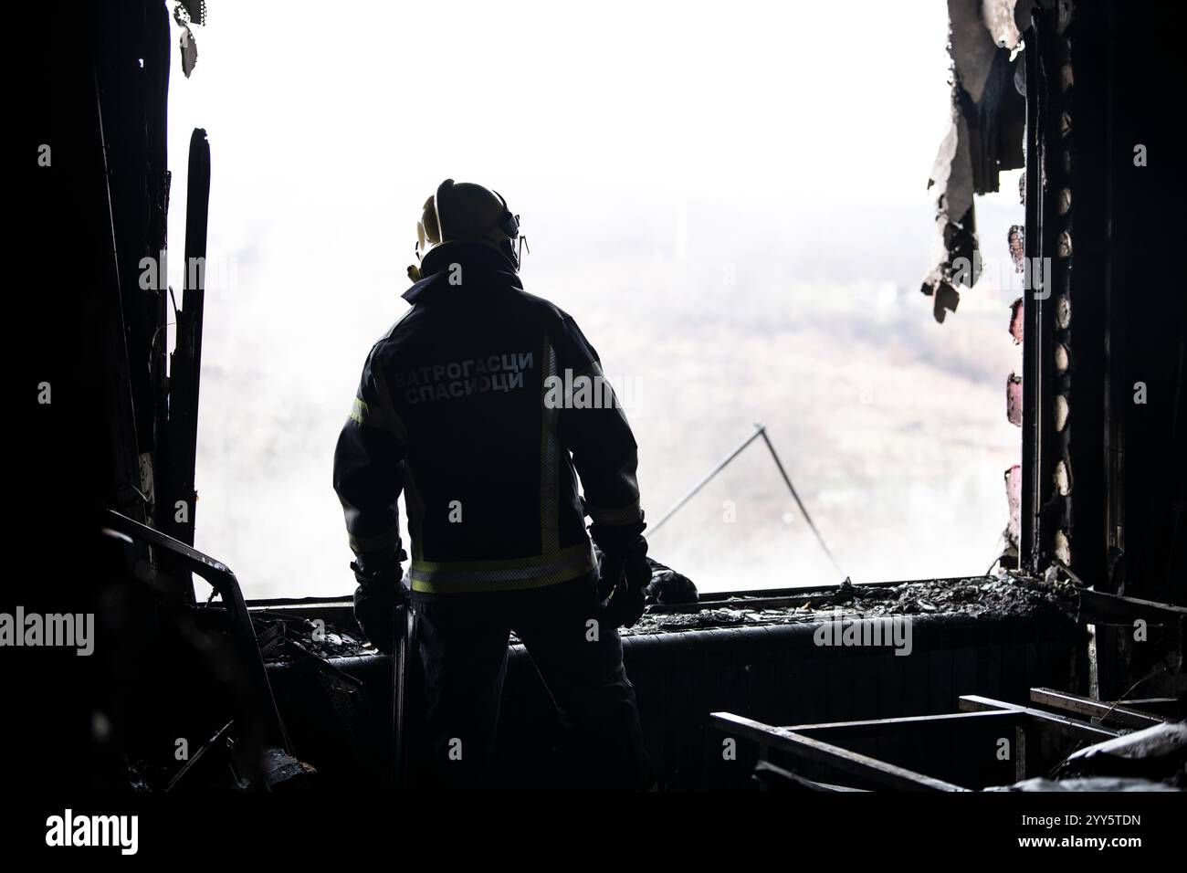 A silhouette of firefighter standing in the dark burned office room ...