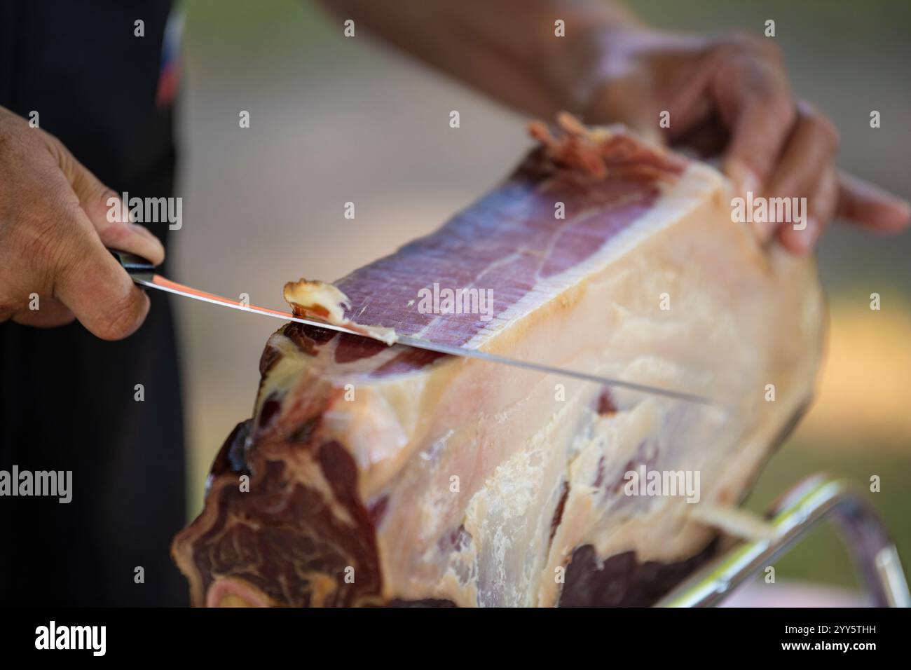 Slicing dry-cured ham prosciutto. Professional cutter carving slices ...