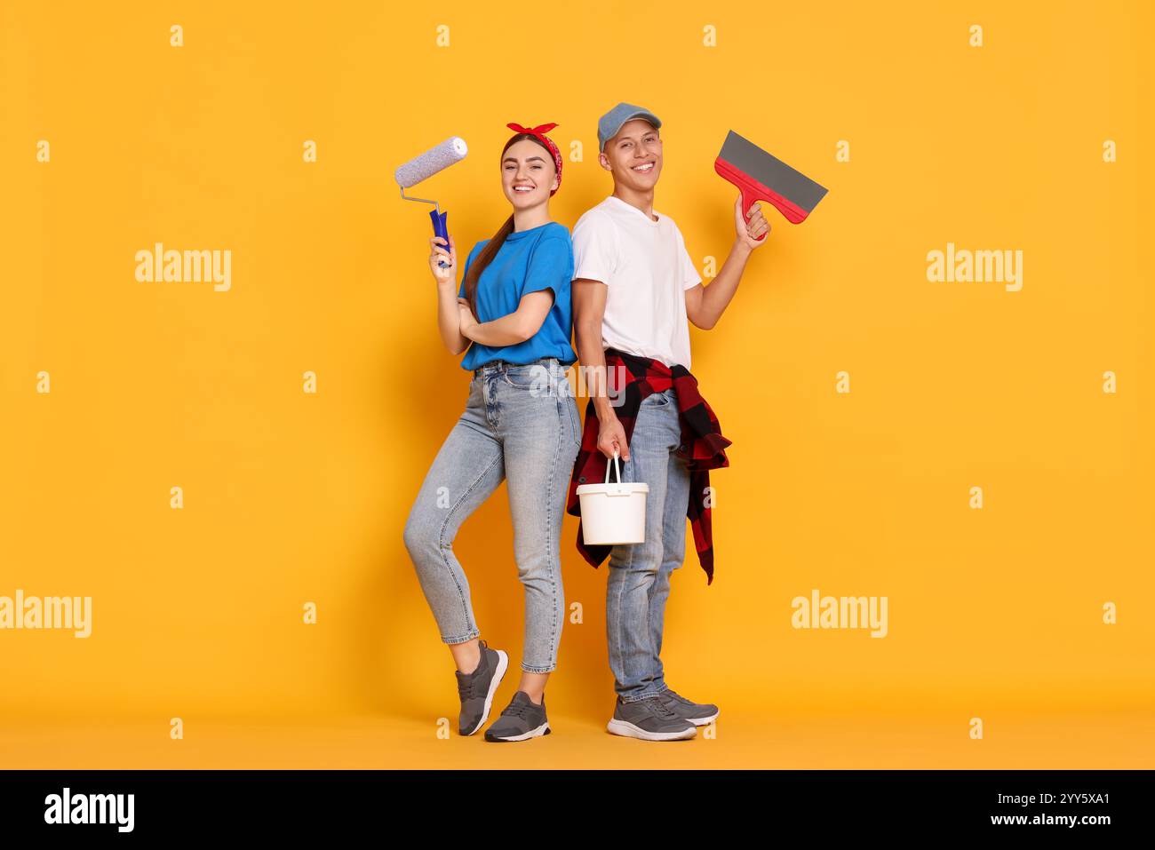 Professional decorator. Man and woman with different tools on orange ...