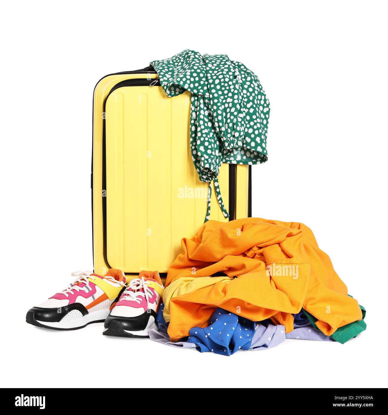 Yellow suitcase, pile of different messy clothes and sneakers isolated ...