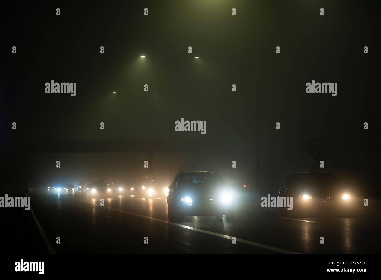 Vehicle headlights moving through thick fog on the highway at night ...